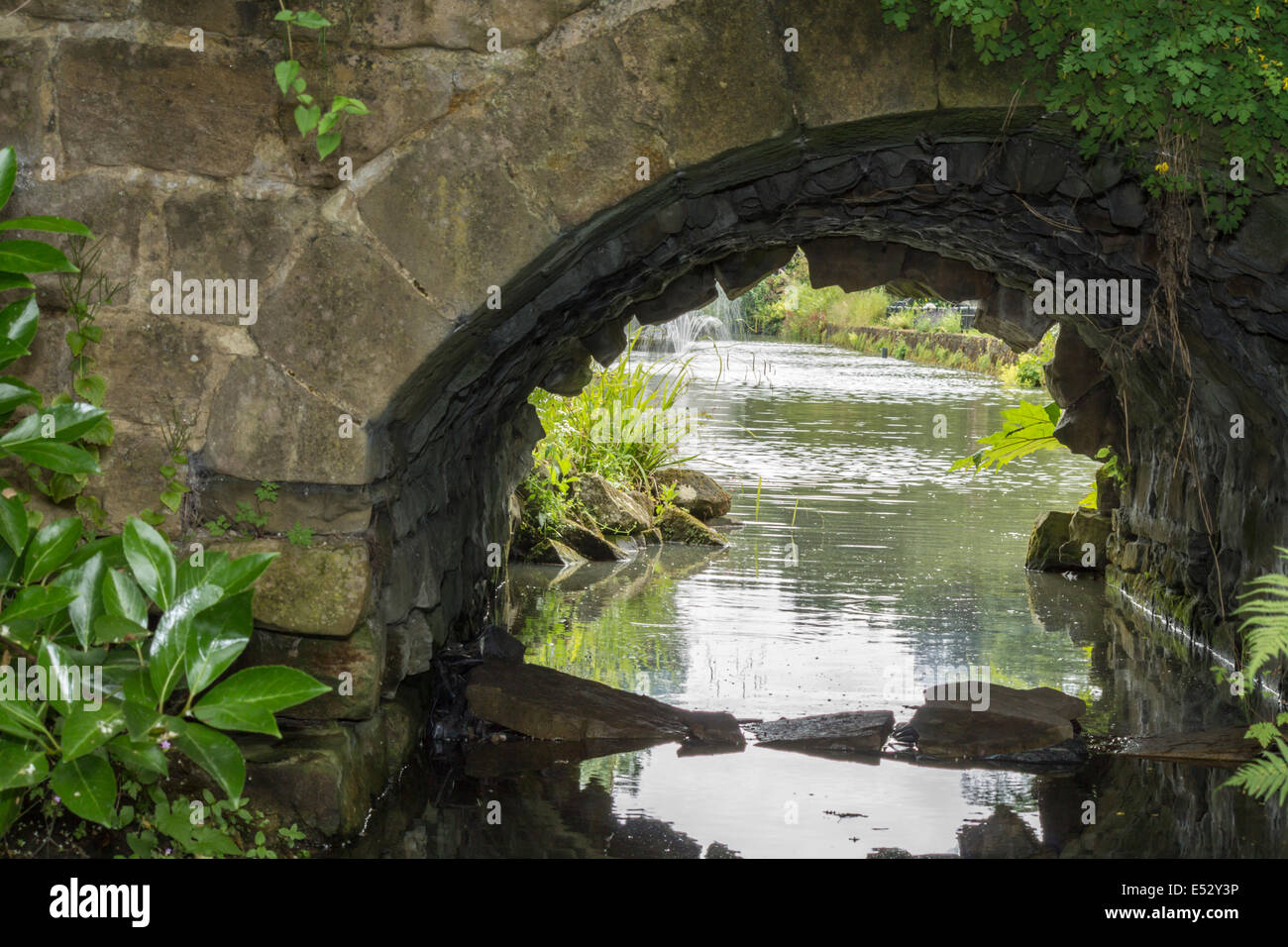 A stone bridge over a stream leading into a lake Stock Photo - Alamy