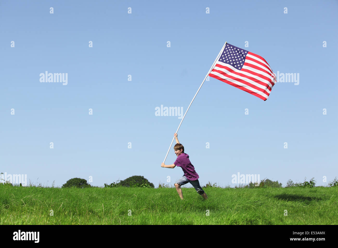 Patriotic young boy running with a american flag on grenn meadow Stock ...