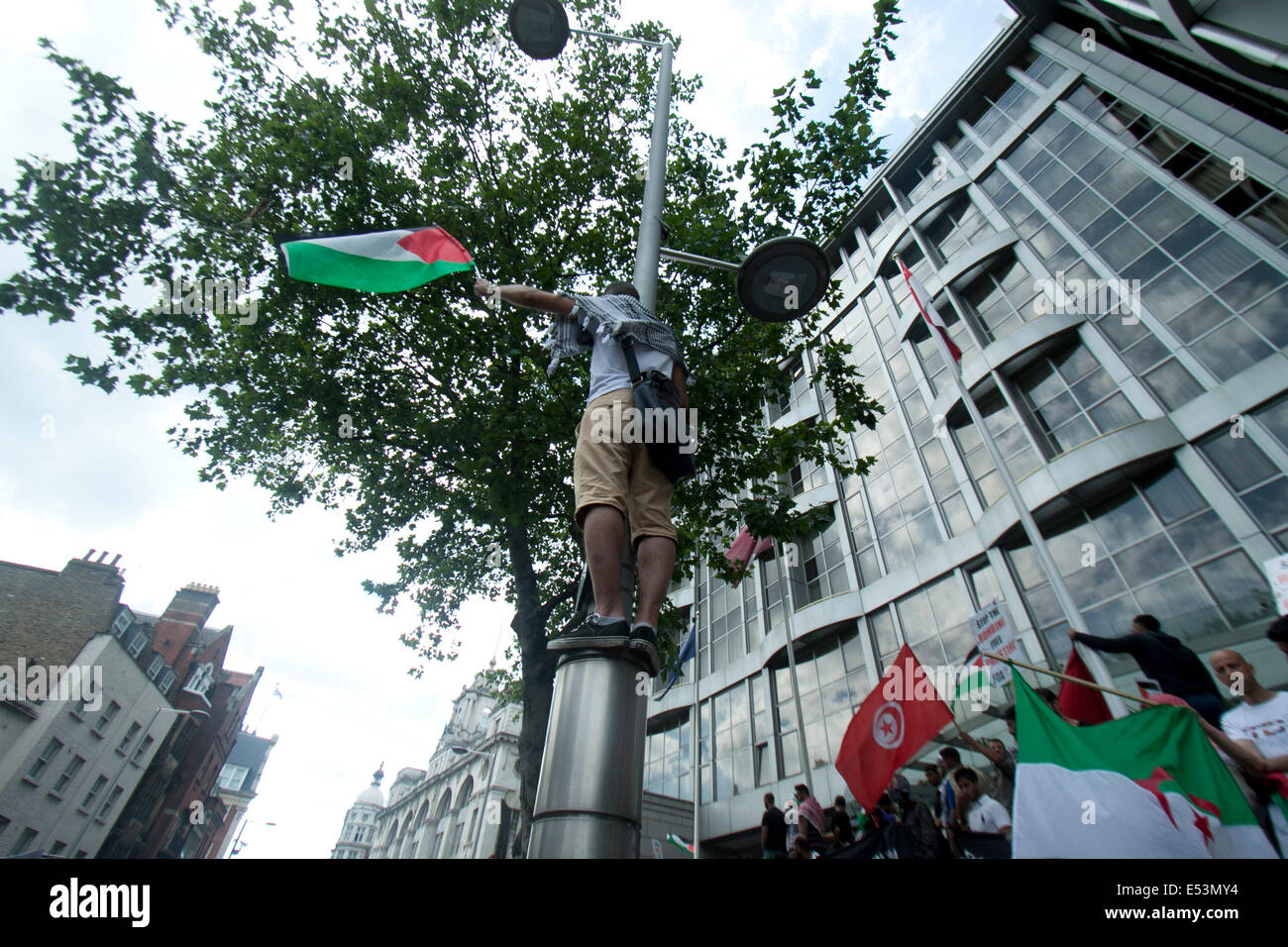 London UK. 19th July 2014. A protester climbs on a lamppost with a flag ...