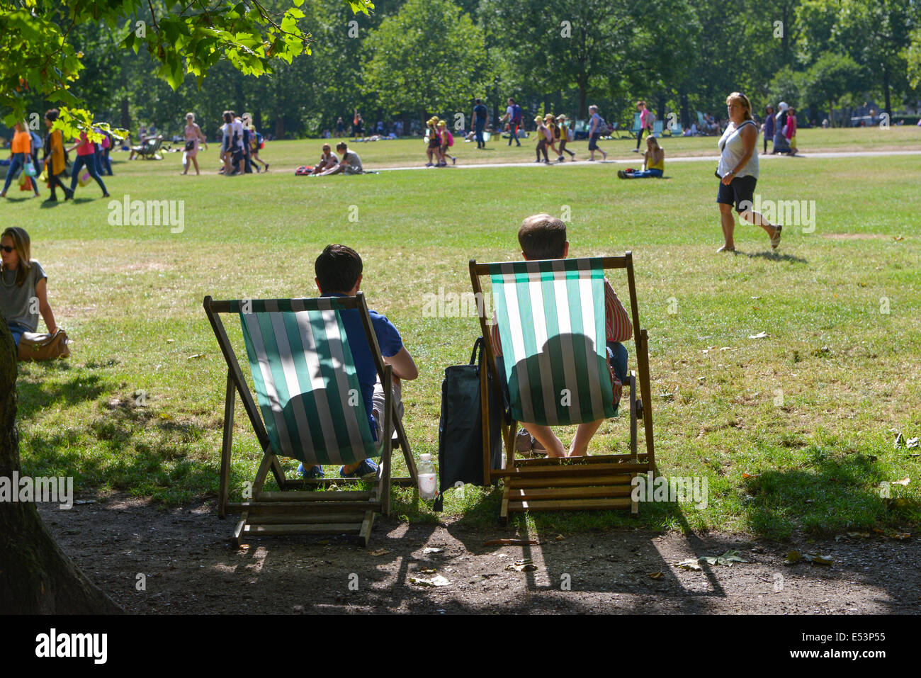 Green Park, London, UK. 19th July 2014. Two people sensibly sit in the ...