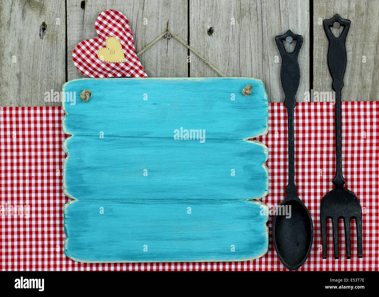 Blank antique blue sign with cast iron spoon and fork and red checkered ...
