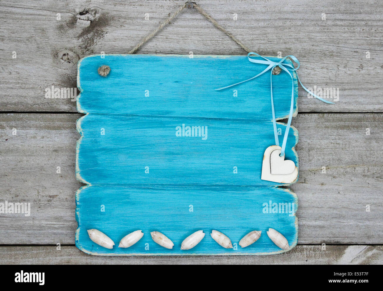 Blank teal blue sign with seashells and hearts hanging on rustic wooden ...