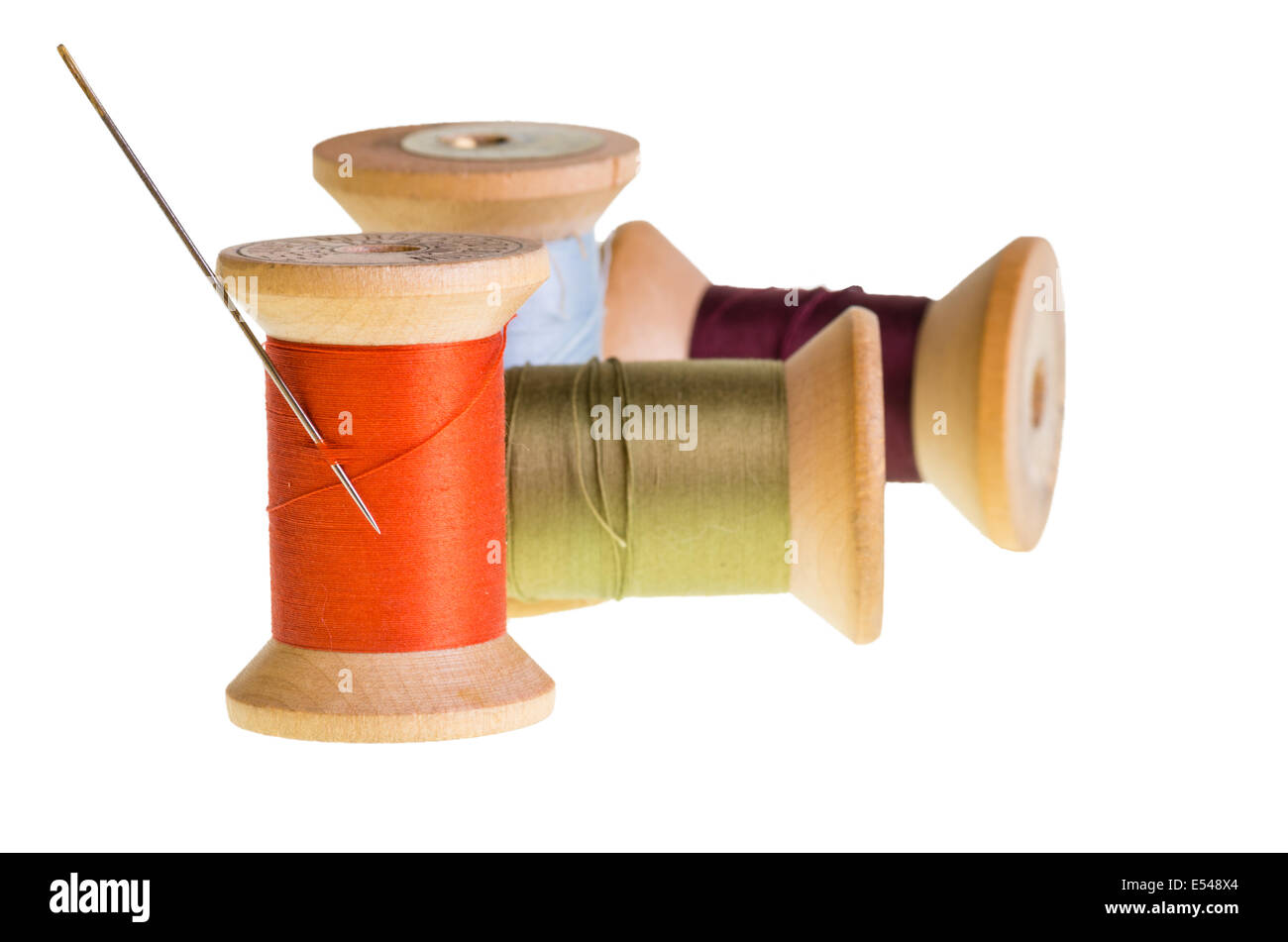 Four spools of sewing thread with a needle Stock Photo - Alamy