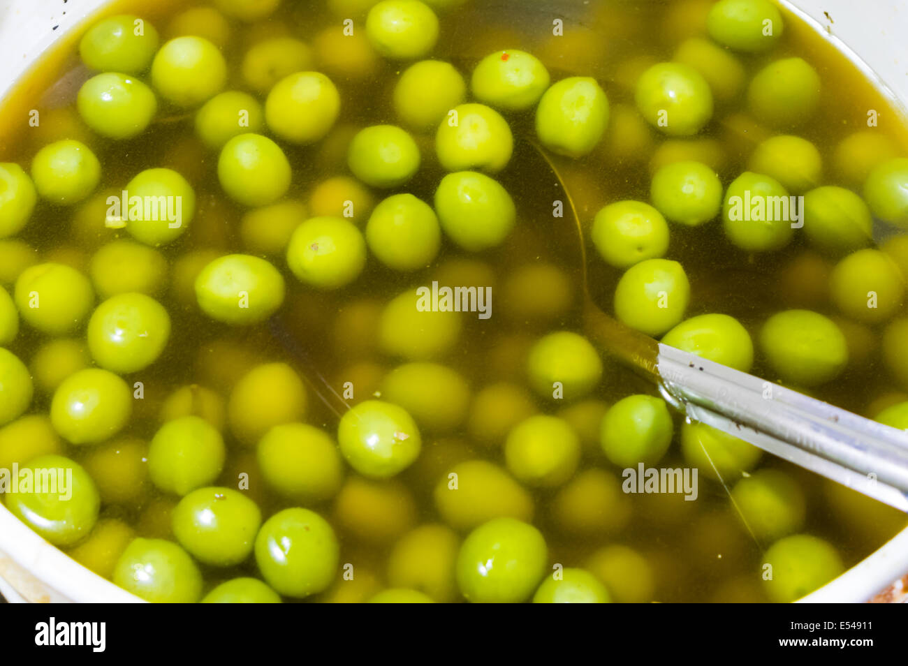 A bucket of olives with spoon and brine Stock Photo - Alamy