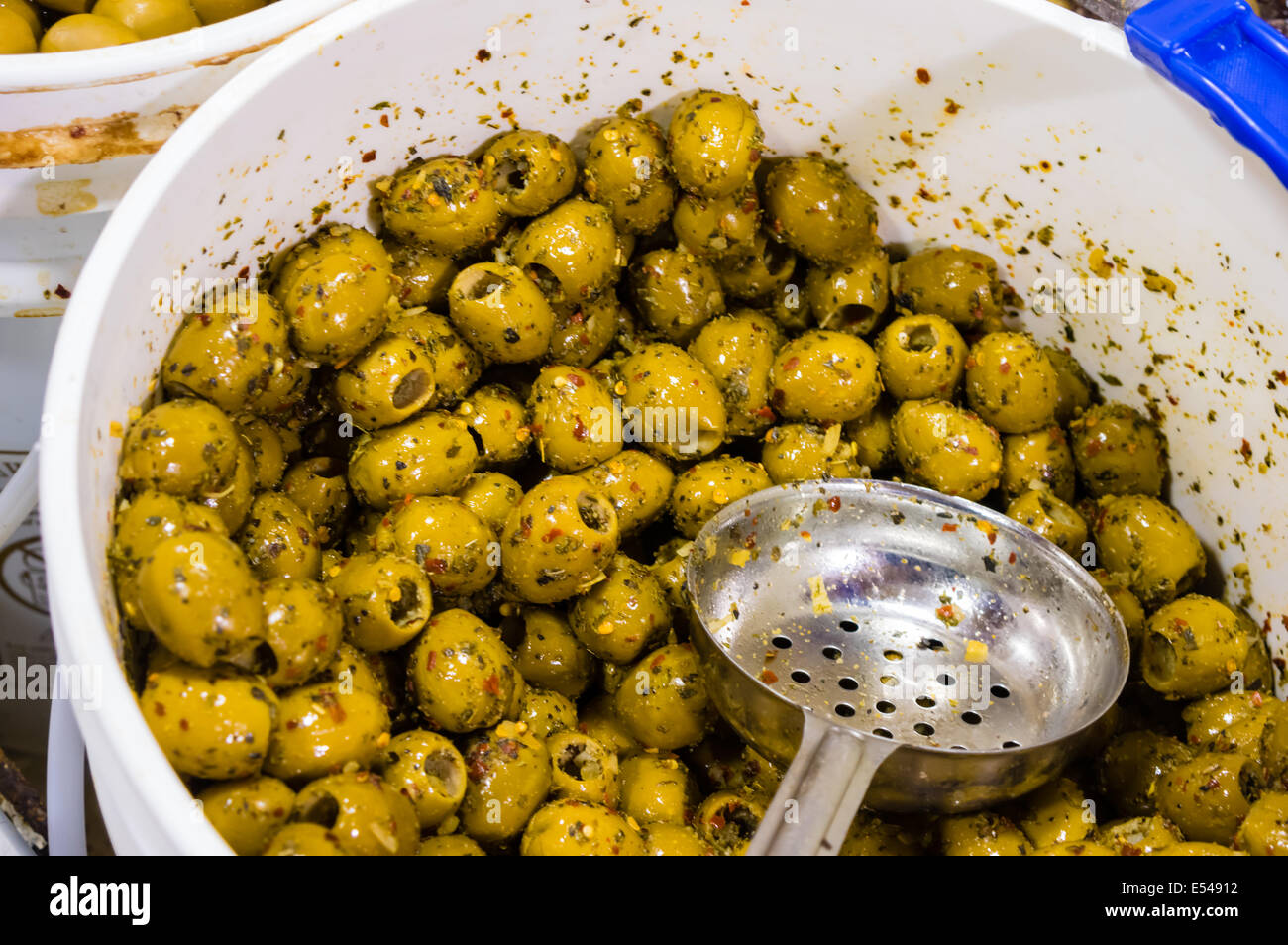 A bucket of olives with spoon and brine Stock Photo - Alamy