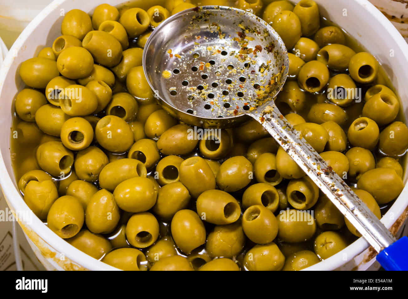 A bucket of olives with spoon and brine Stock Photo - Alamy