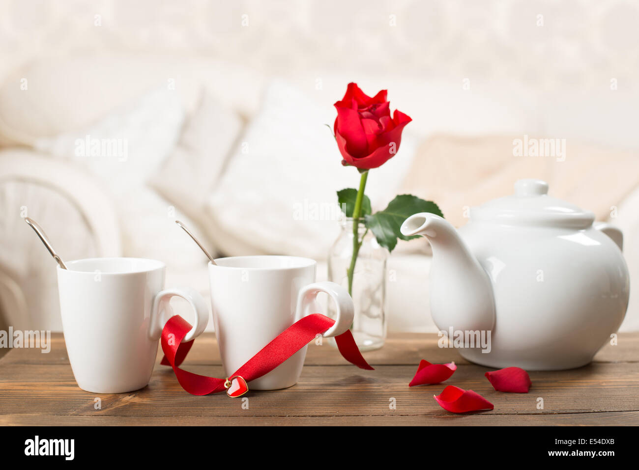 Teapot and teacups with single red rose stem Stock Photo - Alamy