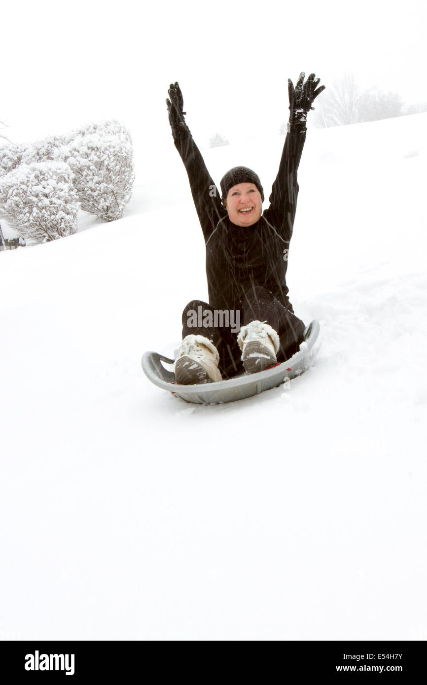 Mature woman sledding on a snowy hill in winter Stock Photo - Alamy