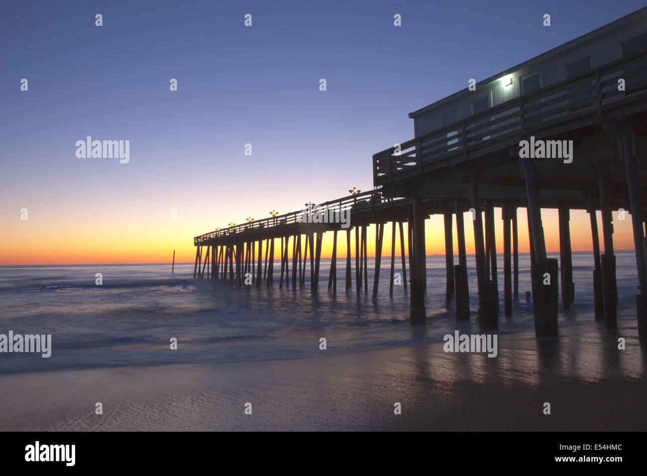 Sunrise breaking over a pier stretching into the ocean Stock Photo - Alamy