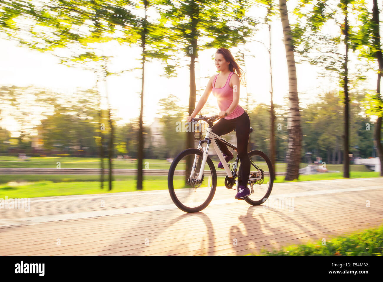young woman driving on bicycle in evening park toned image Stock Photo ...