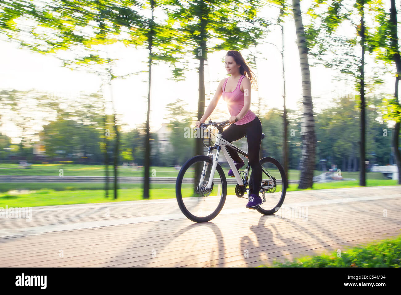young woman driving on bicycle in evening park Stock Photo - Alamy