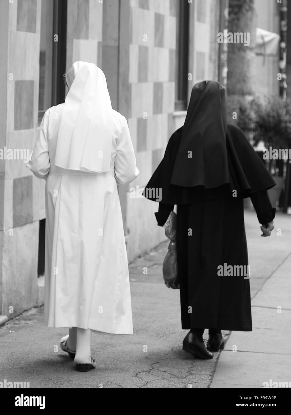 two old sisters with black suit and white dress walking on the road ...