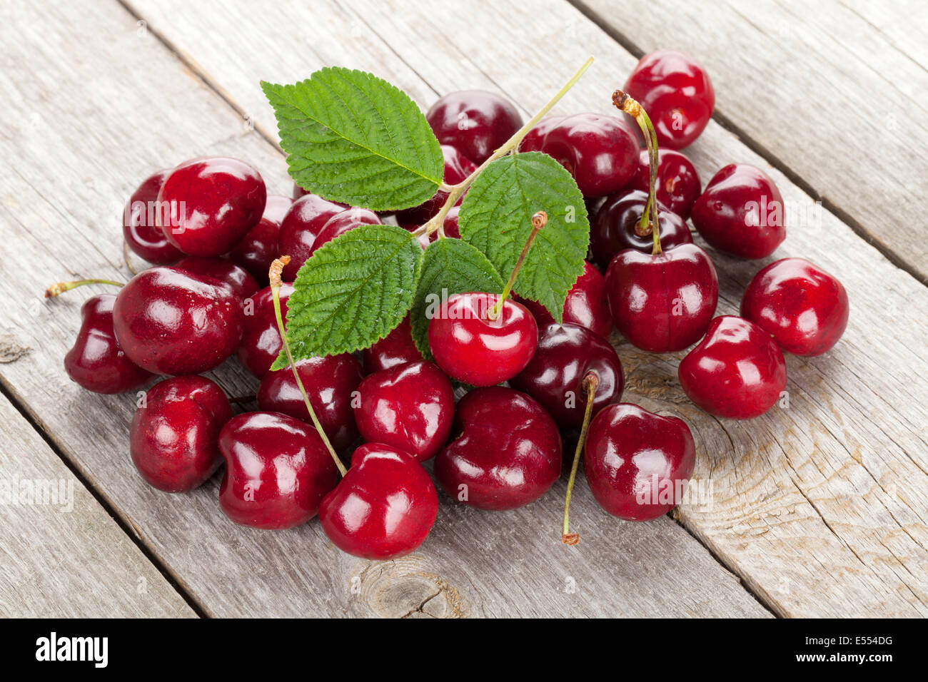 Ripe cherries on wooden table with green leaves Stock Photo - Alamy