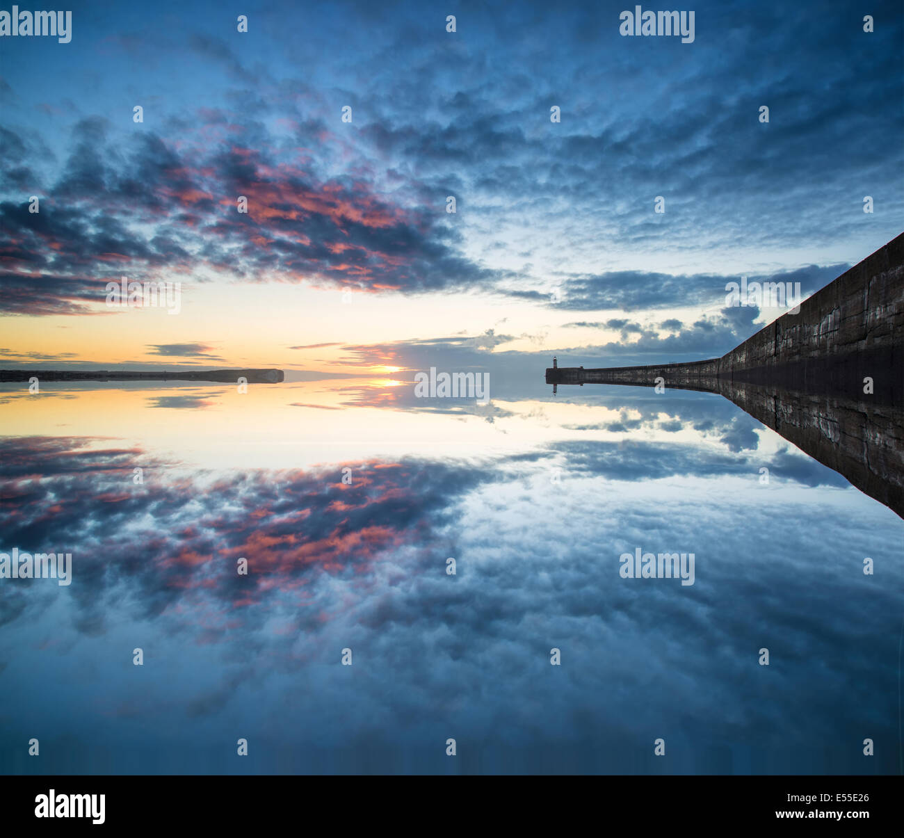 Stunning sunrise over ocean with lighthouse and harbor wall Stock Photo ...