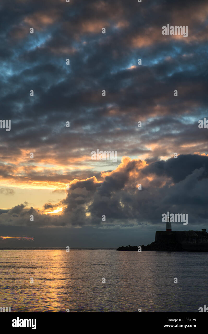 Stunning sunrise over ocean with lighthouse and harbor wall Stock Photo ...