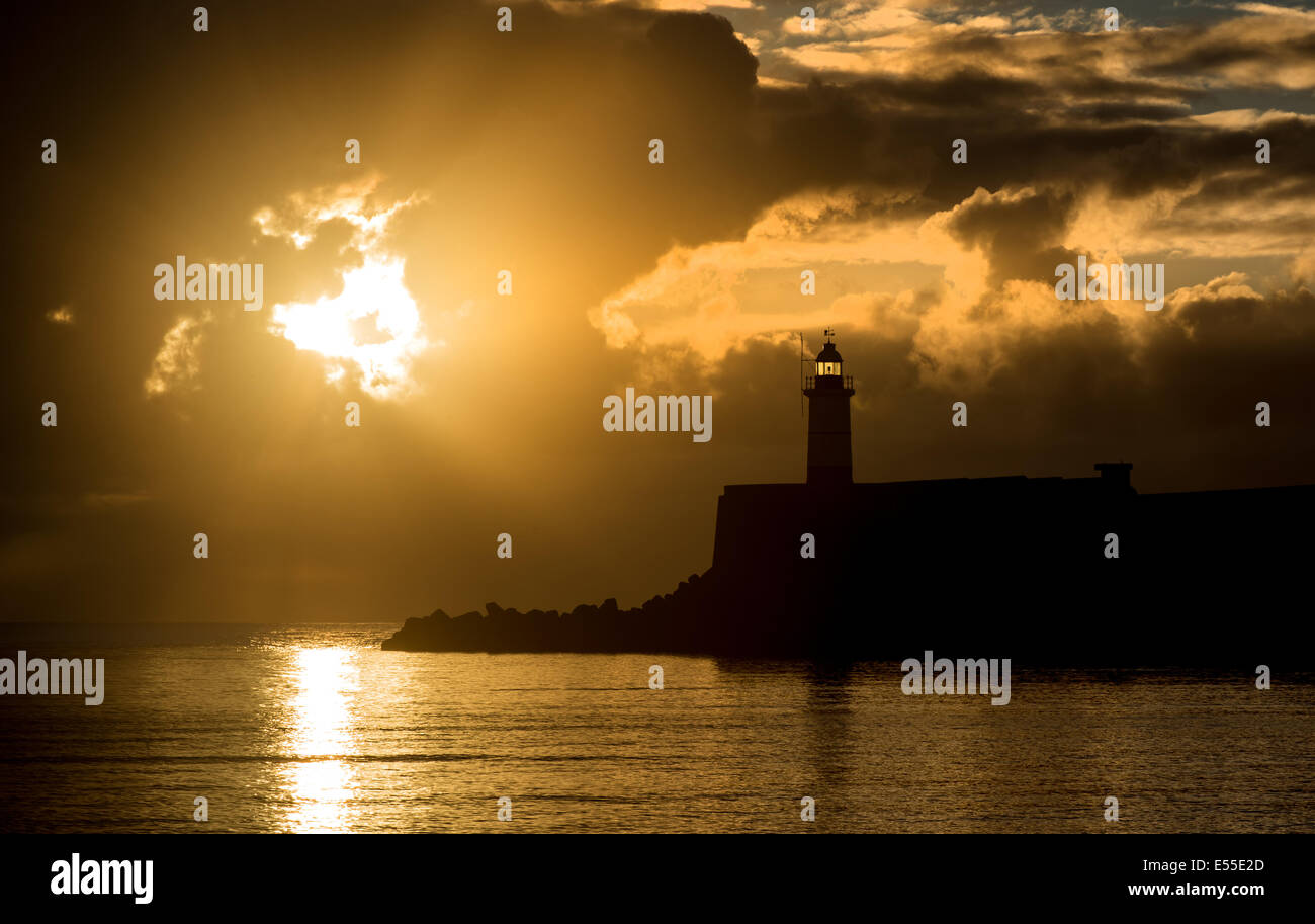 Stunning sunrise over ocean with lighthouse and harbor wall Stock Photo ...