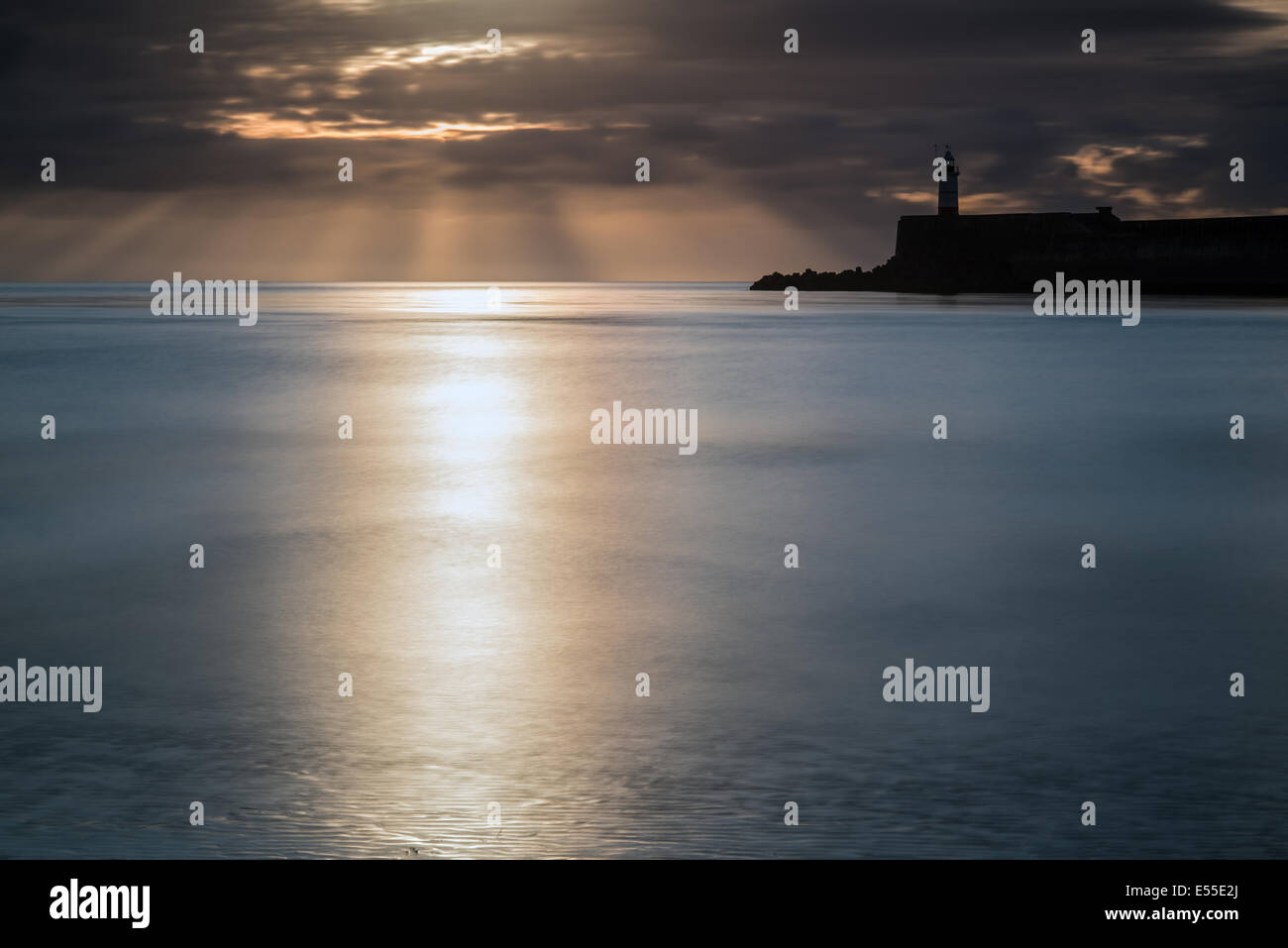 Stunning sunrise over ocean with lighthouse and harbor wall Stock Photo ...
