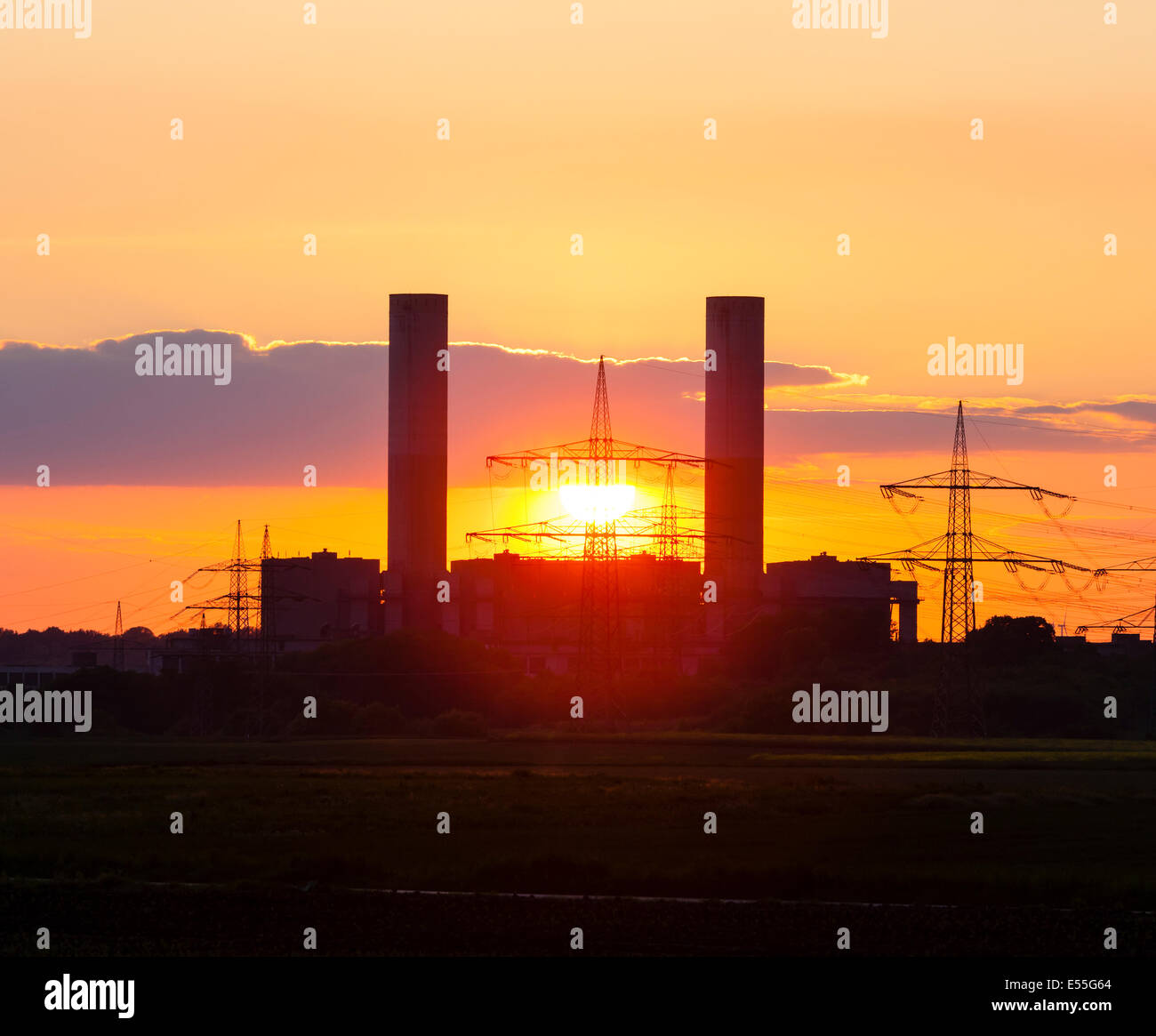 The sun setting between the chimneys of a coal-fired power station ...