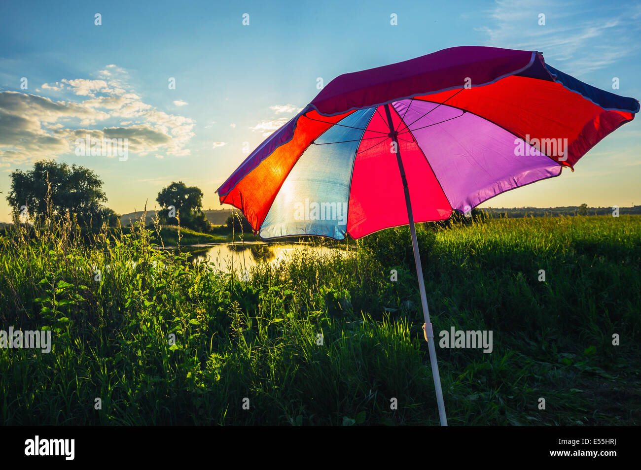 Colorful umbrella in the summer at sunset on a background of the sky ...
