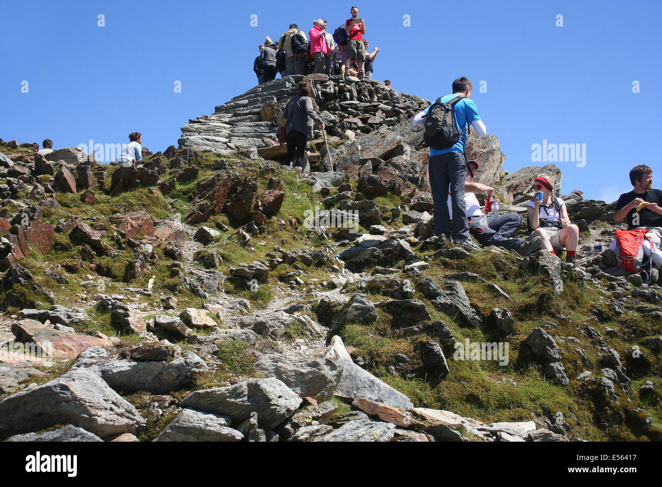 Walkers crowd onto the summit cairn of Mount Snowdon on a warm summer's ...
