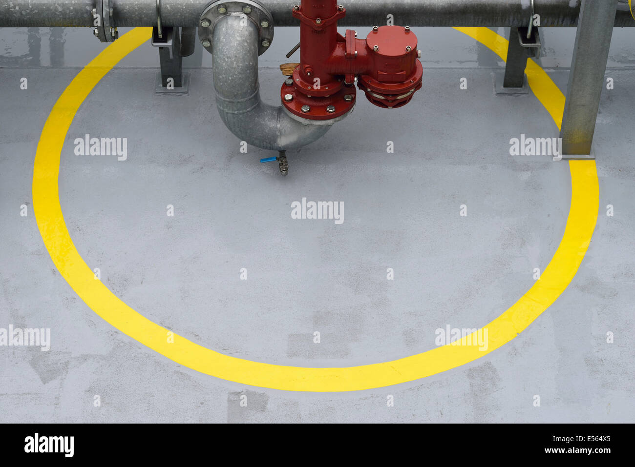 Detail of parts of an oil tanker pipe work showing ppe yellow warning ...