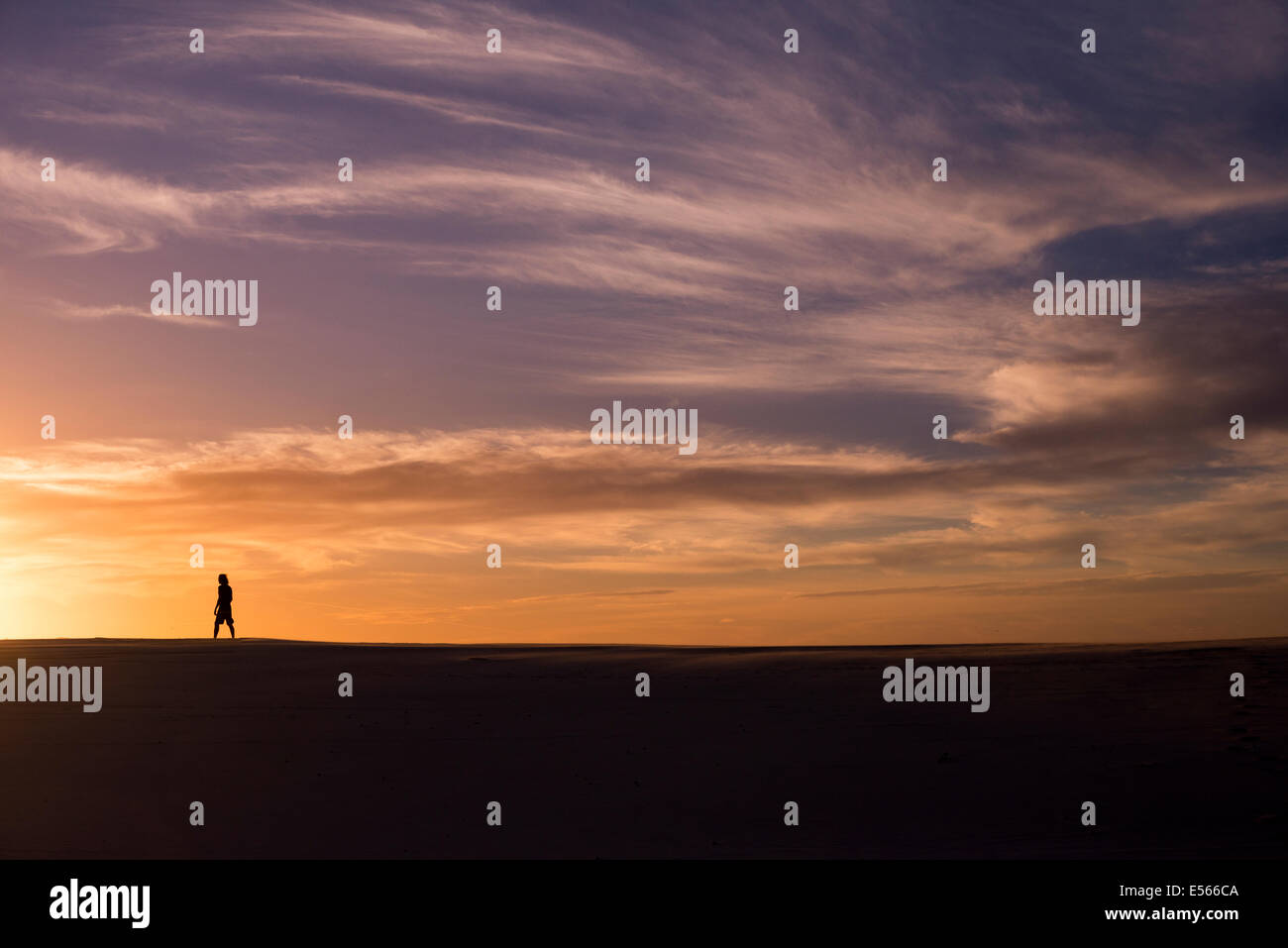 Man on the horizon walking towards the sunset Stock Photo - Alamy