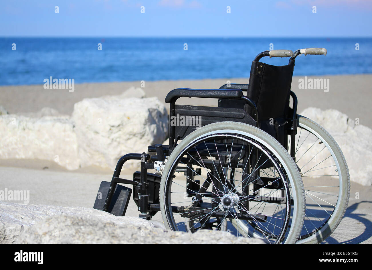 black wheelchair on the rocks of the blue sea in summer Stock Photo - Alamy