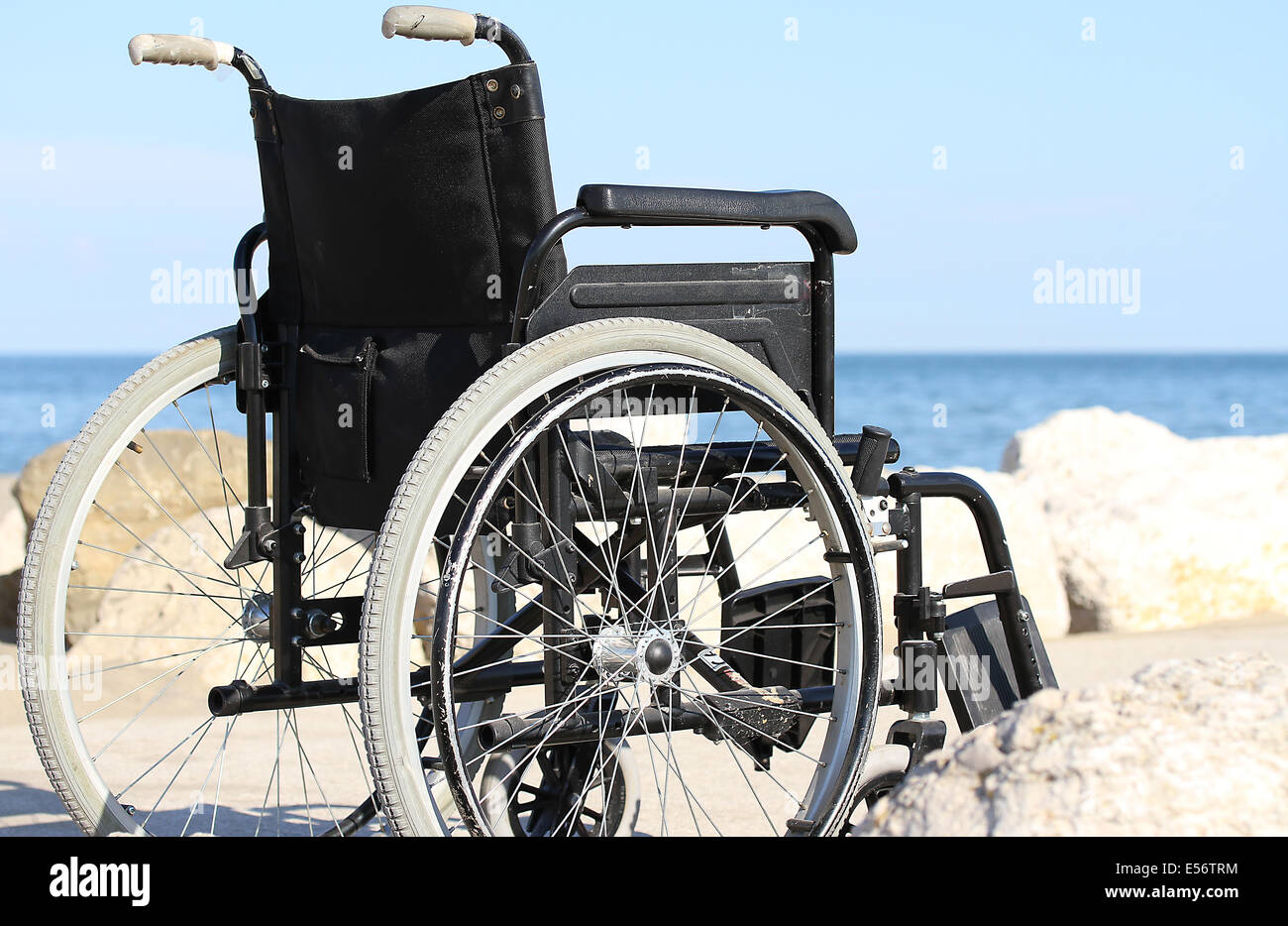 black wheelchair on the rocks near the blue sea Stock Photo - Alamy