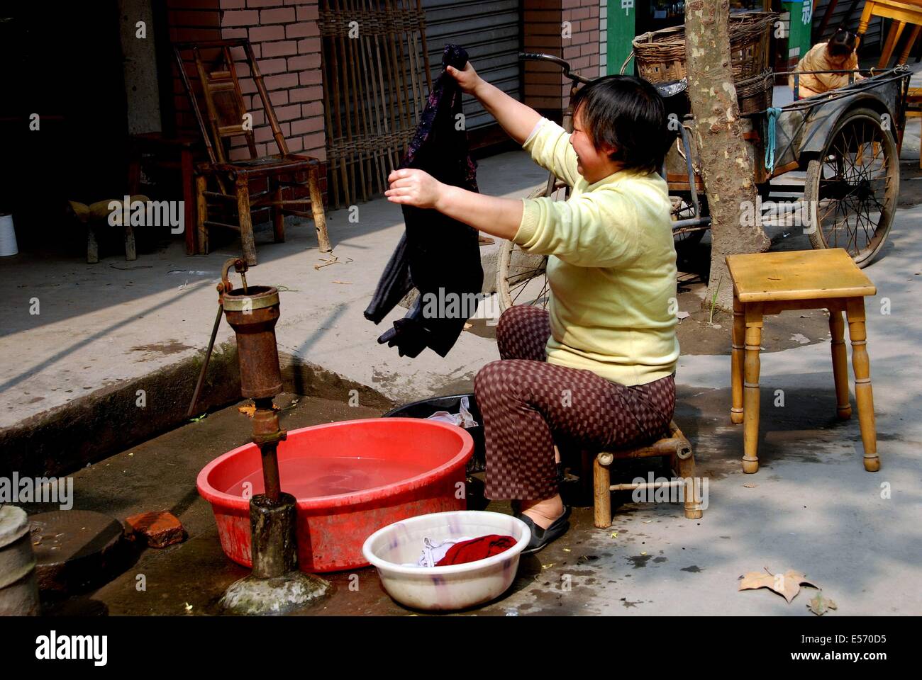Wan Jia, China: Woman doing laundry with plastic buckets at at old iron ...