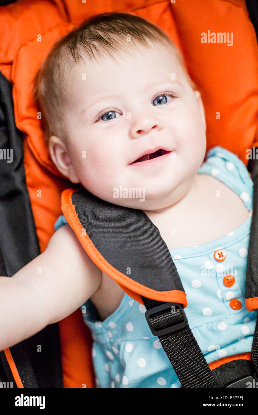 Cute baby girl sitting in orange stroller Stock Photo - Alamy