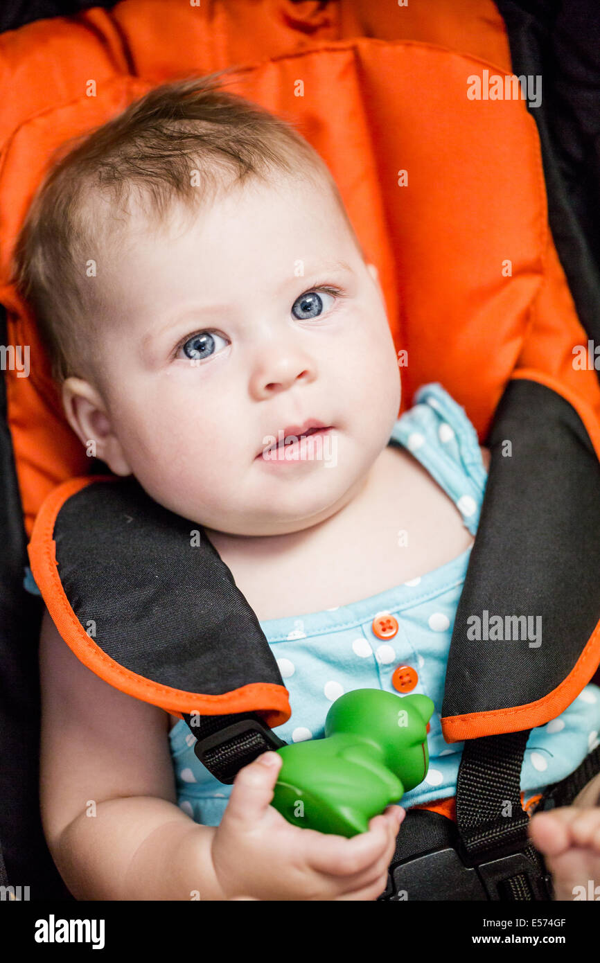 Cute baby girl sitting in orange stroller Stock Photo - Alamy