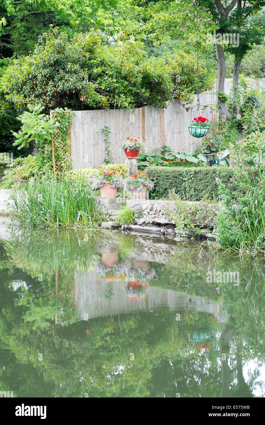 Trees and flowers of riverside garden reflected in water Stock Photo ...