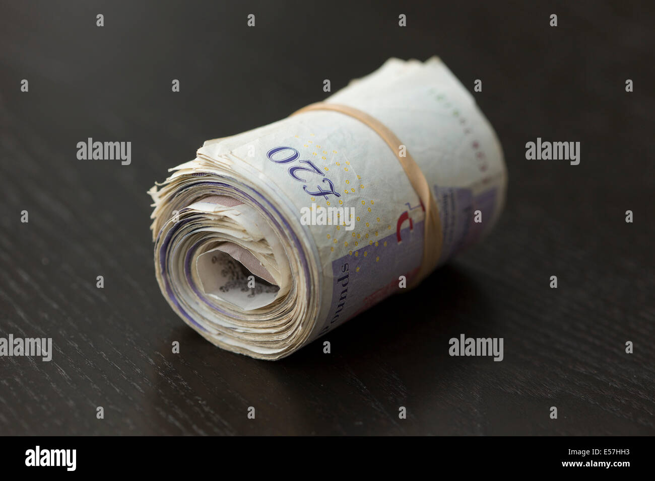 roll of UK money on a black background with a rubber band around Stock ...