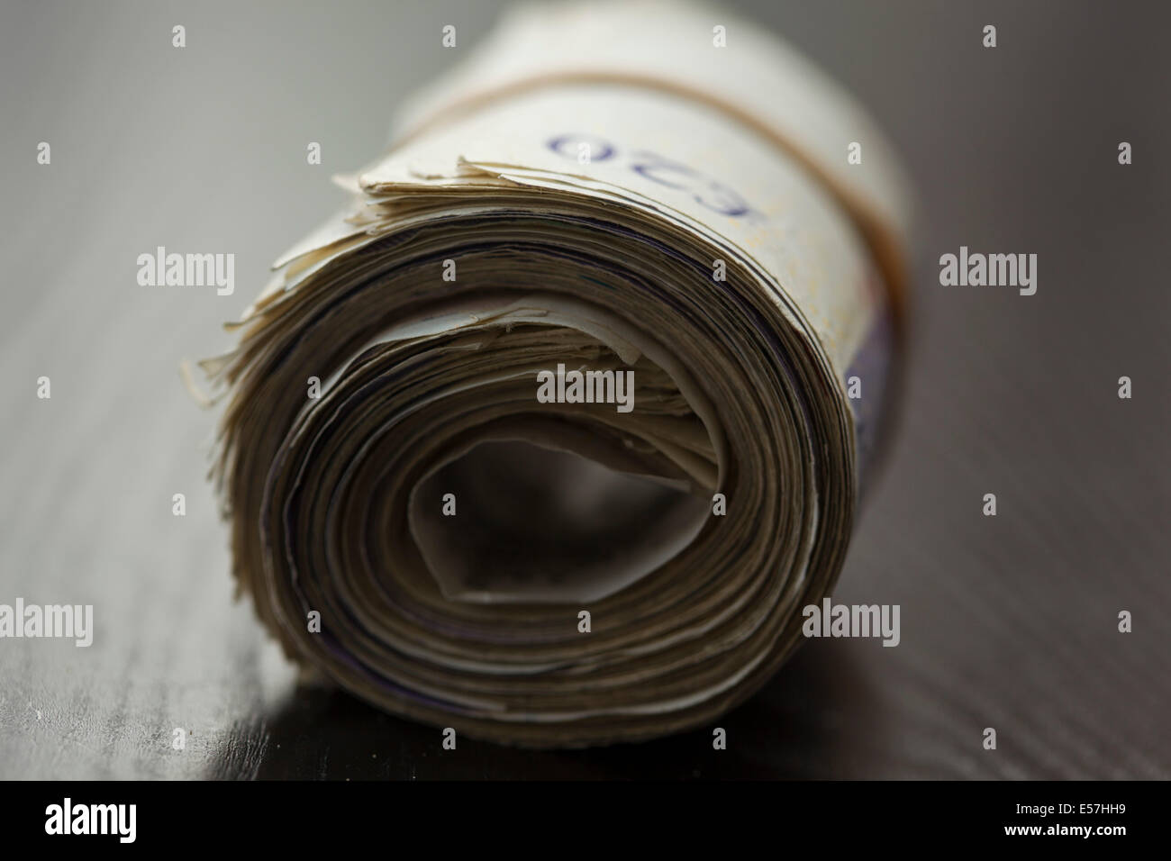 roll of UK money on a black background with a rubber band around Stock ...