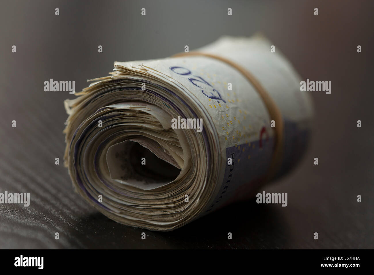 roll of UK money on a black background with a rubber band around Stock ...