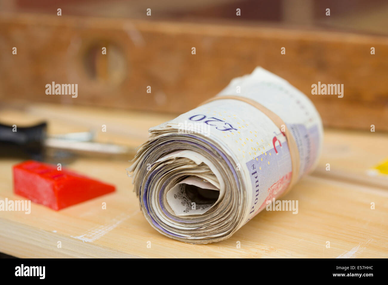 roll of uk banknotes on builders workbench Stock Photo - Alamy