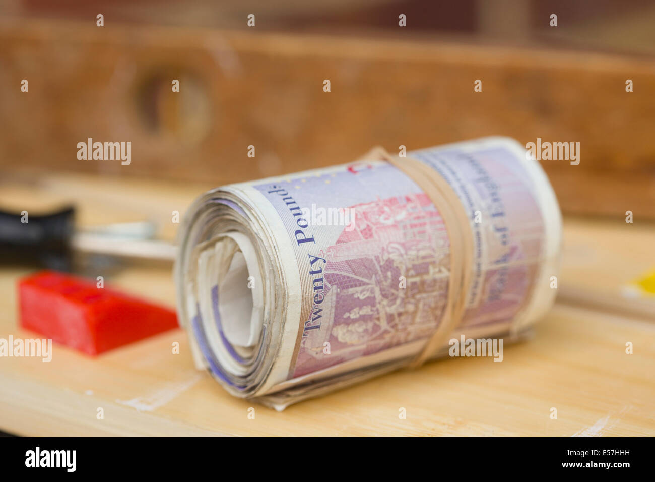 roll of uk banknotes on builders workbench Stock Photo - Alamy