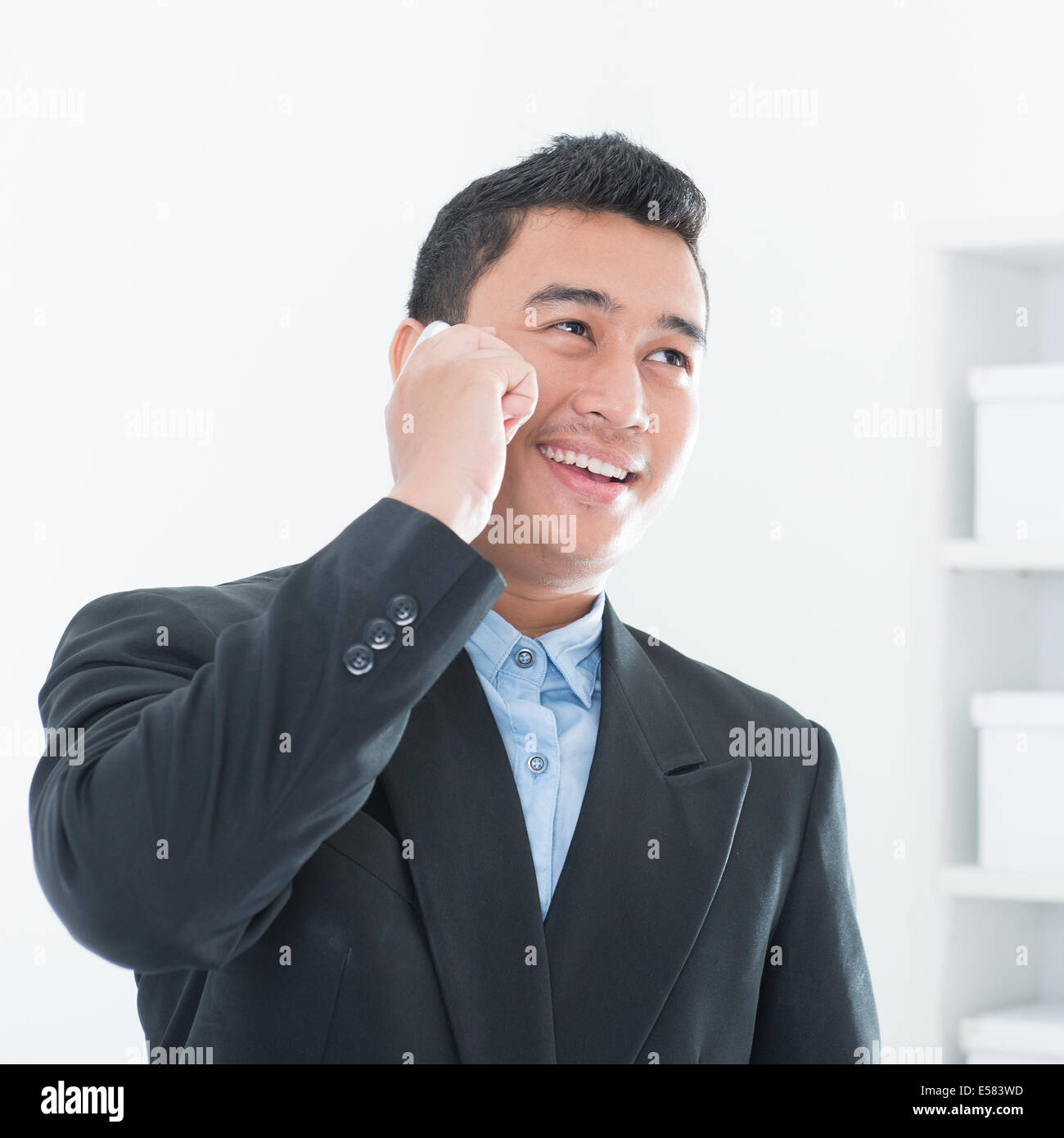 Southeast Asian business executive talking on smartphone in office ...