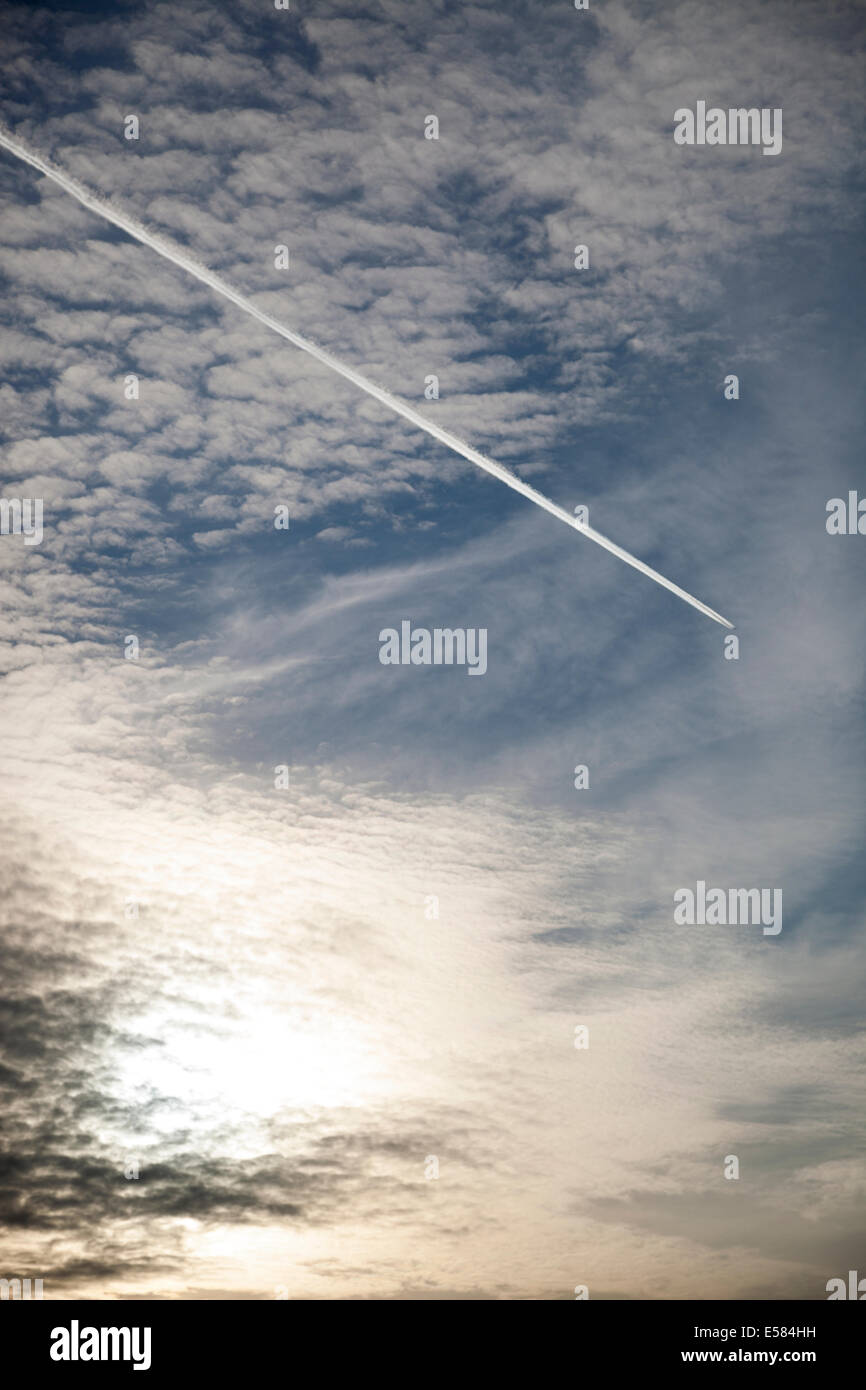 Contrail from jets at sunset in England, UK with Altocumulus clouds ...