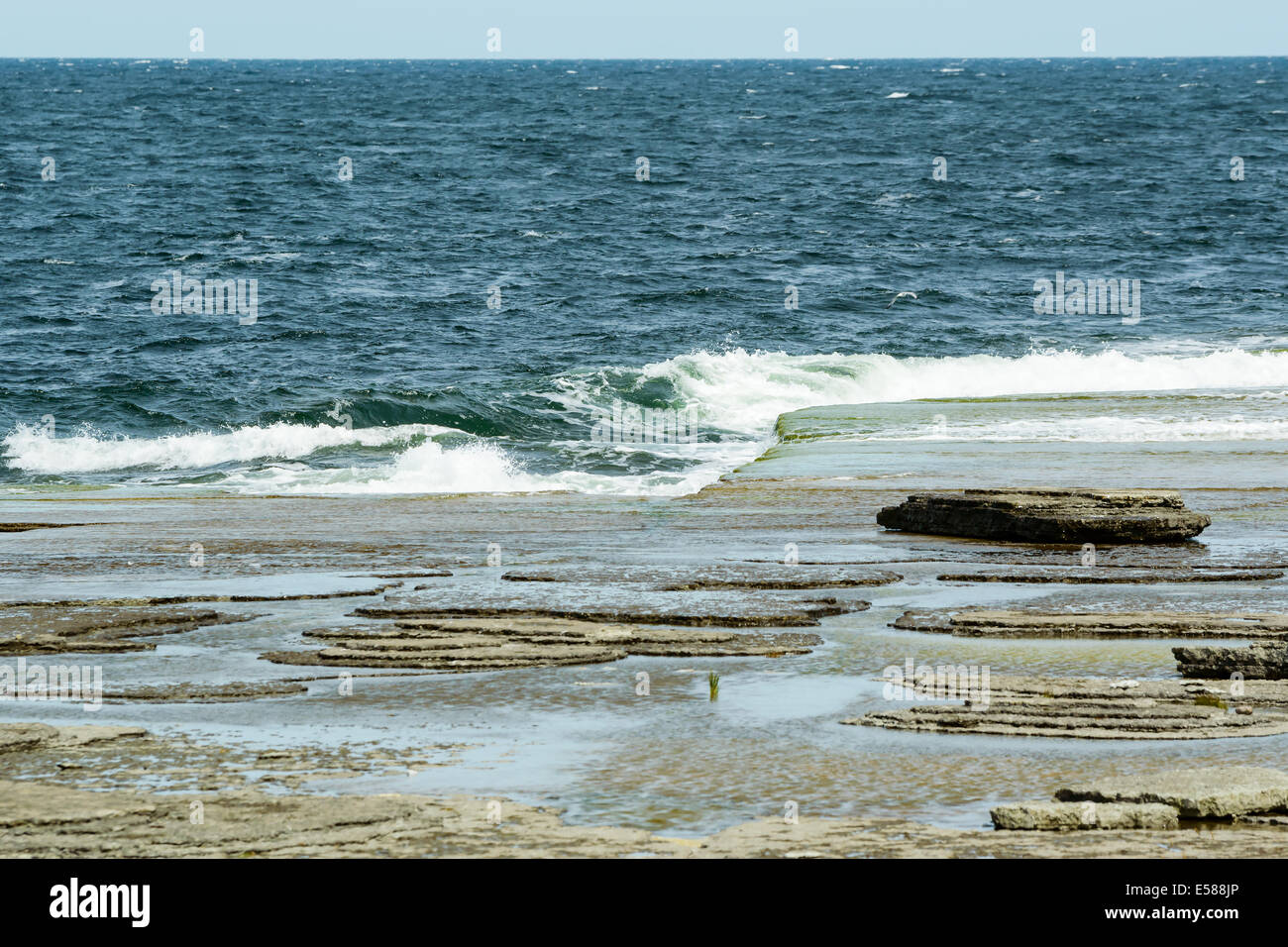 Small summer waves hitting limestone beach while breaking Stock Photo ...