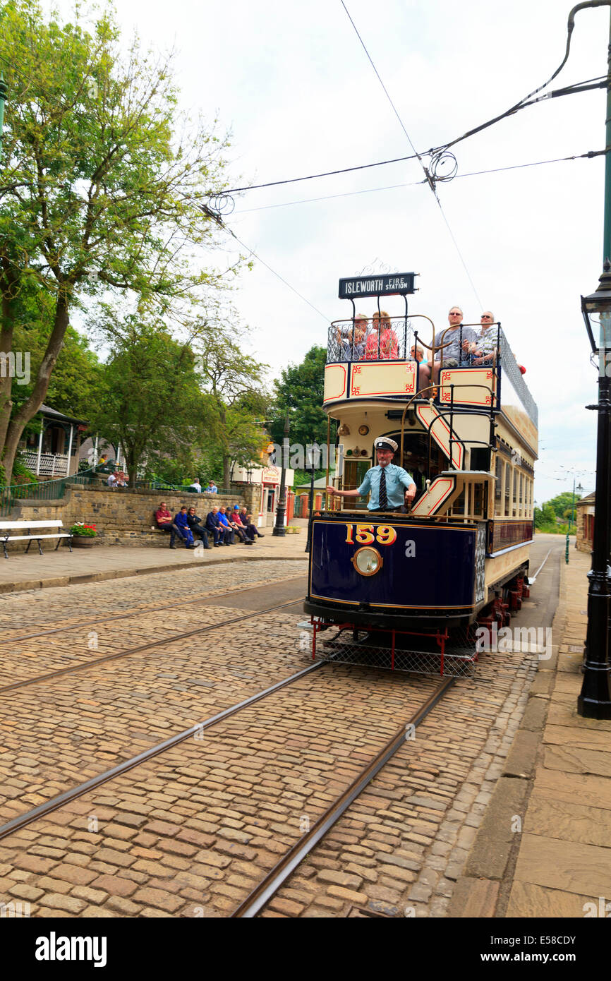 Open top tram operating along the cobbled street at Crich Tramway ...