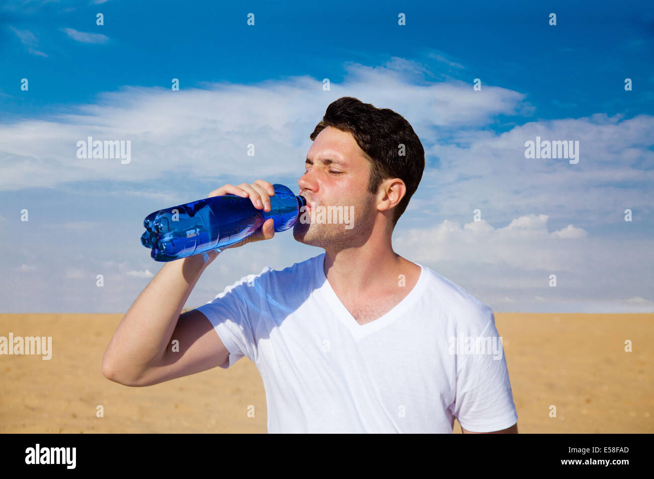 A man drinking water over desert landscape Stock Photo - Alamy