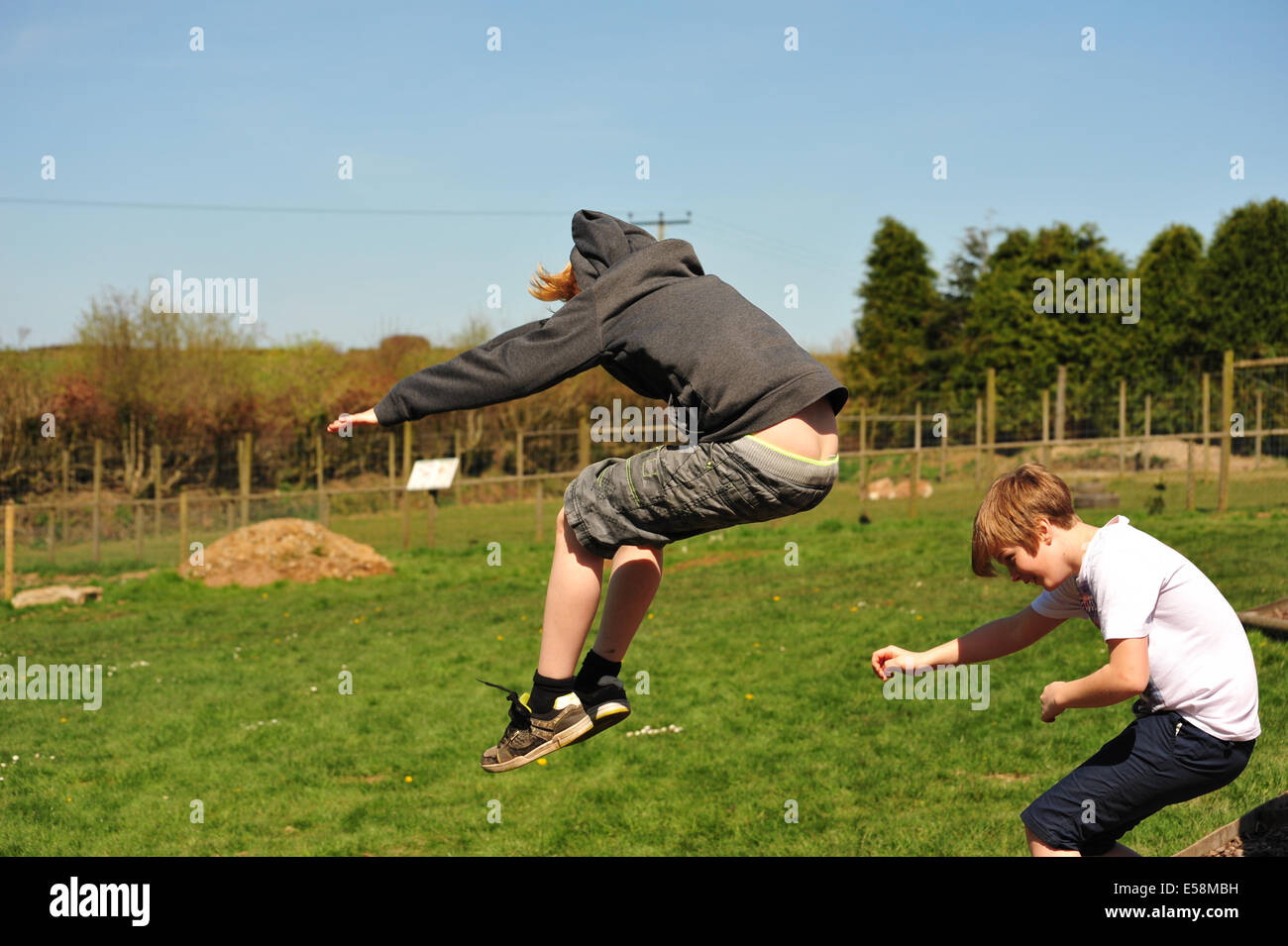 two boys jumping off a swing Stock Photo - Alamy