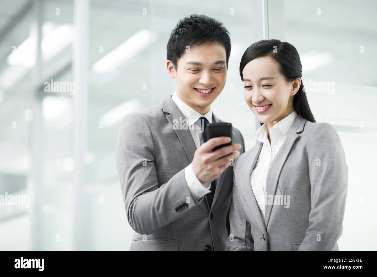 Happy business partners with smart phone Stock Photo - Alamy
