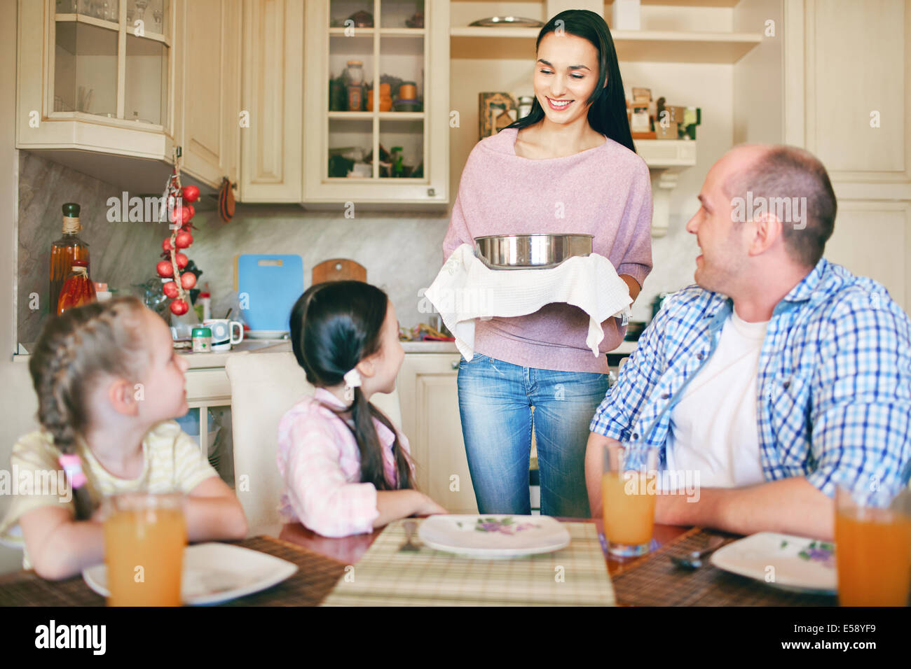 Happy family of four going to have meal in the kitchen Stock Photo - Alamy