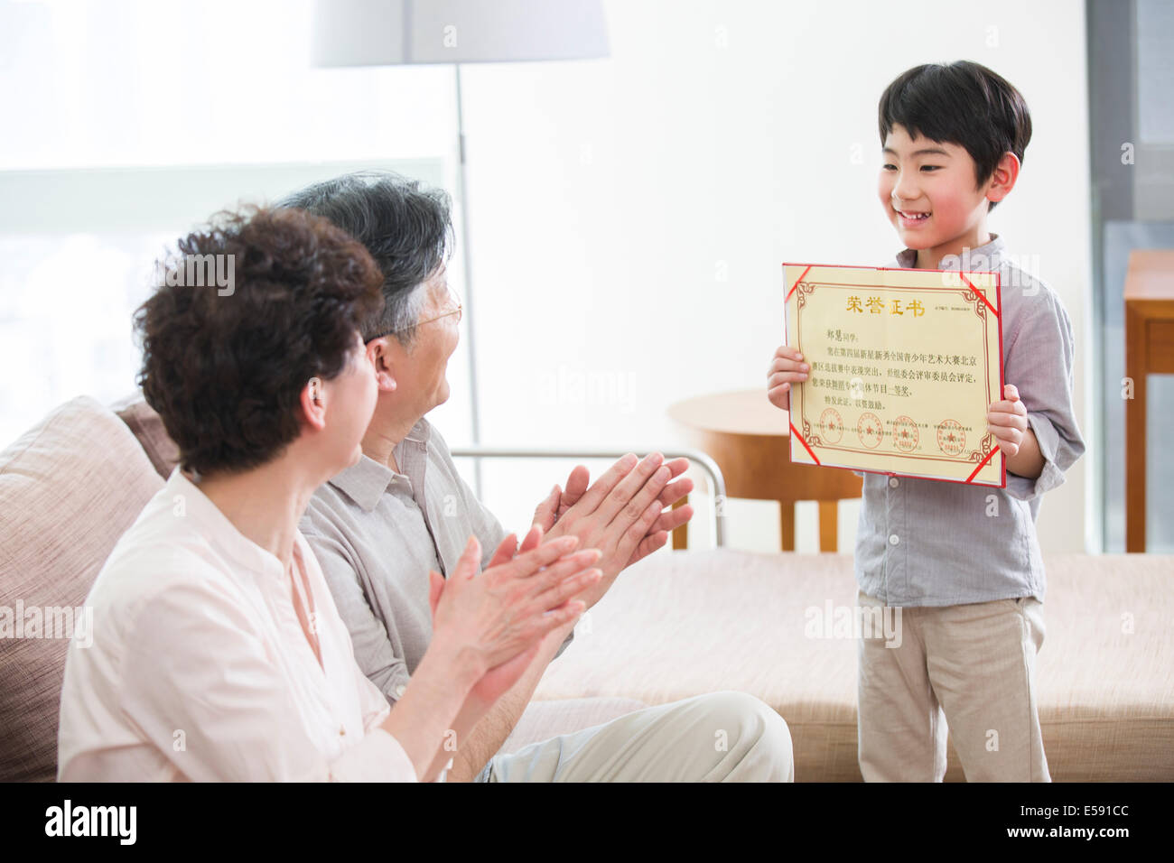 Cute boy showing certificate of merit to grandparents Stock Photo - Alamy