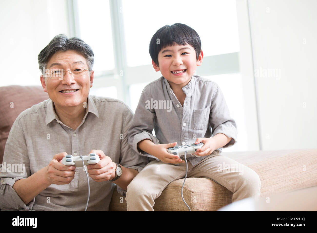 Cheerful grandfather and grandson playing video game Stock Photo - Alamy