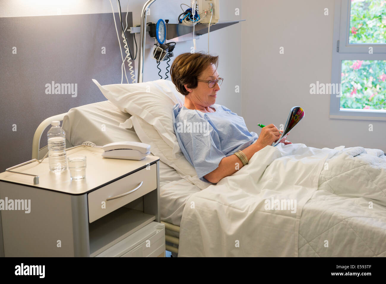 Woman writing on hospital bed Stock Photo - Alamy