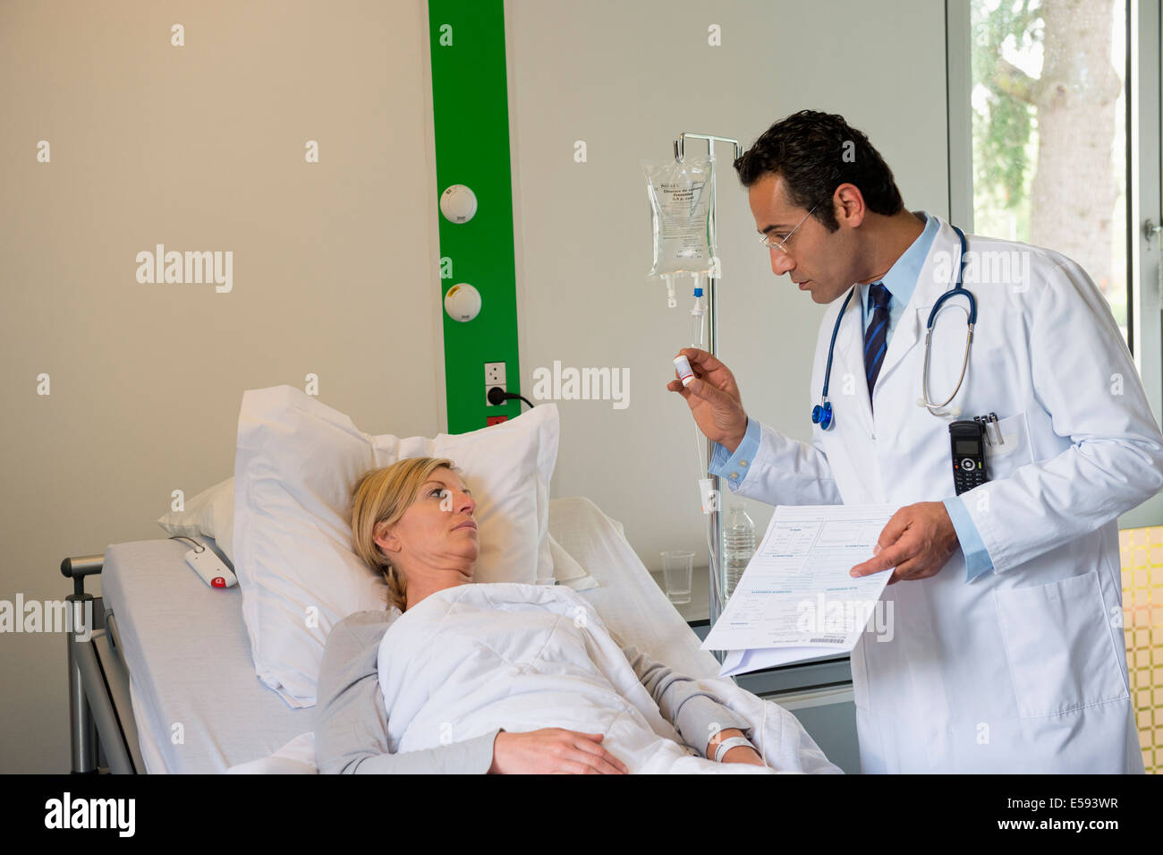 Male doctor giving pills instructions to female patient in hospital bed ...