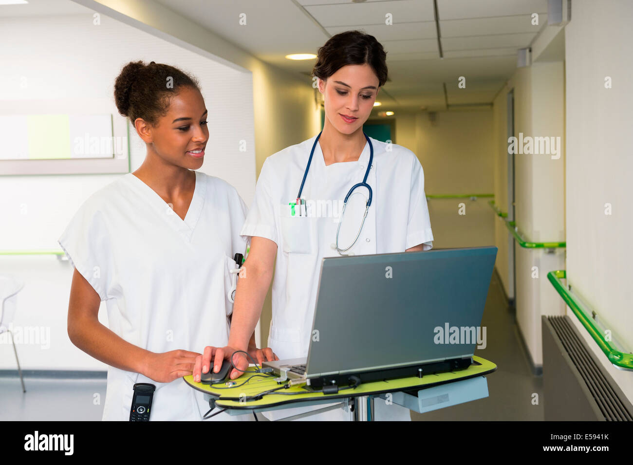 Female doctor and nurse using laptop in hospital corridor Stock Photo ...